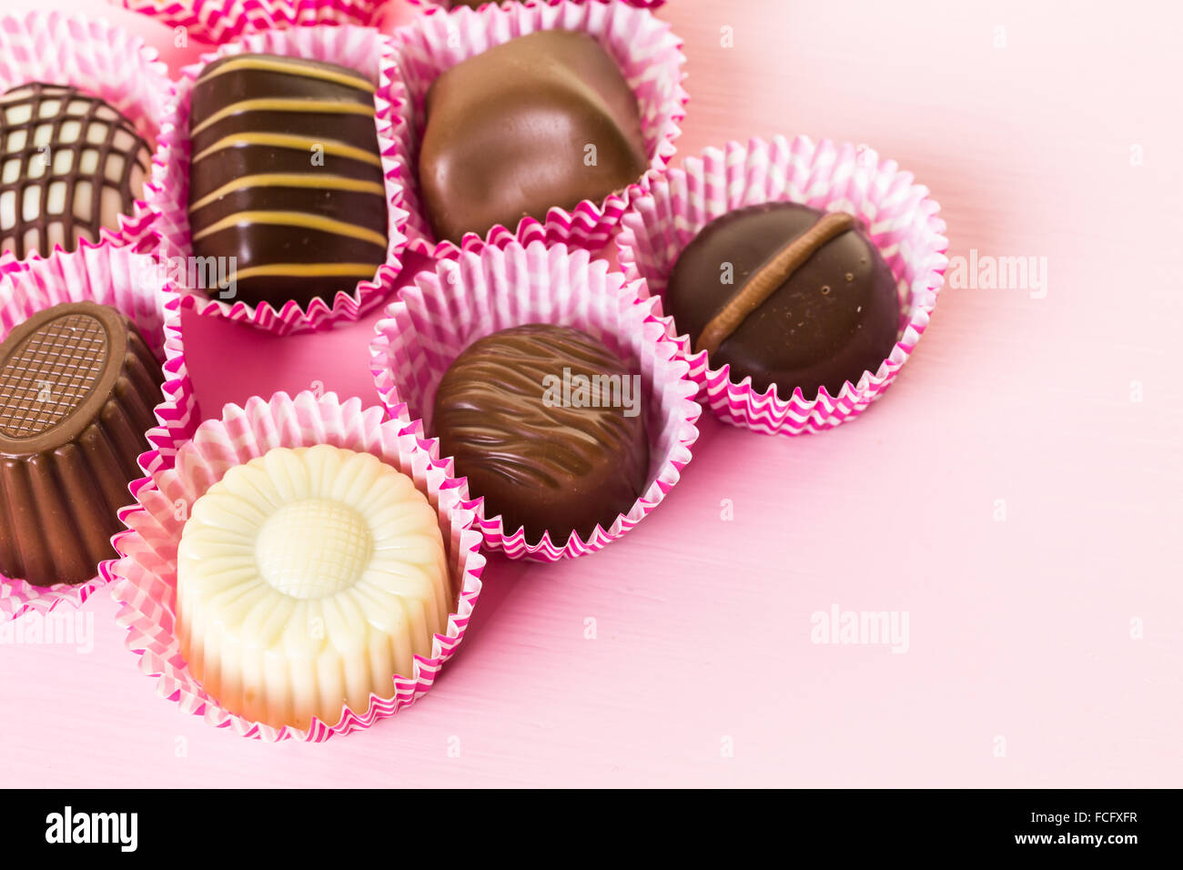 Assorted chocolates on pink background Stock Photo - Alamy