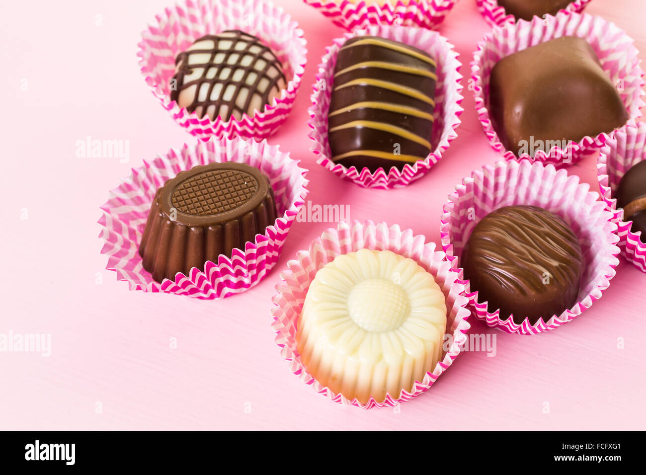 Assorted chocolates on pink background Stock Photo - Alamy