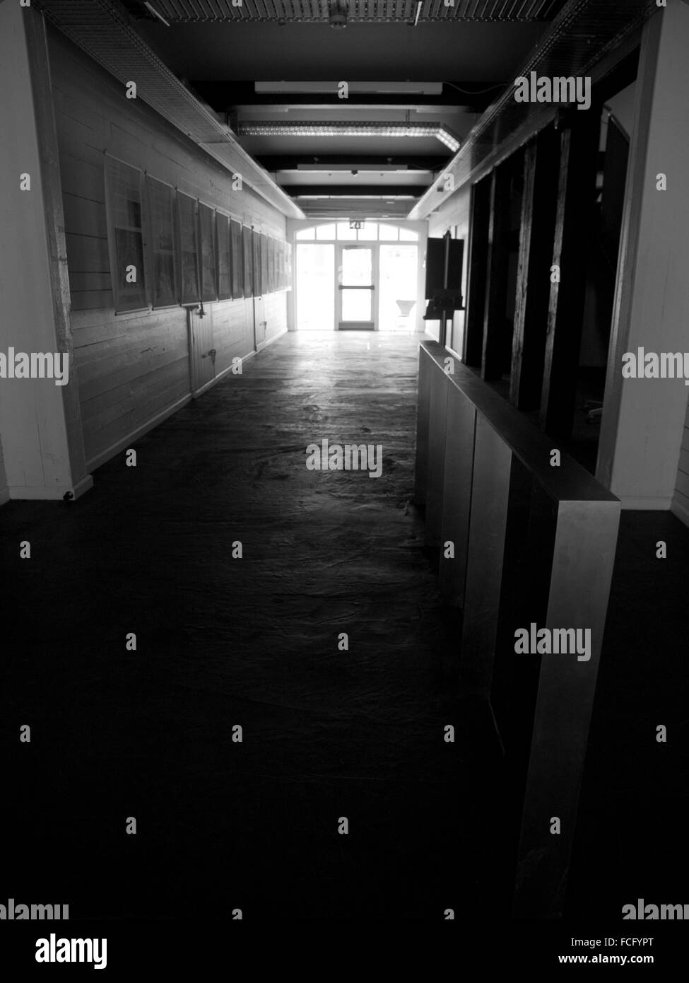 Sunlight coming through a glass door at the end of a long hallway in a ...