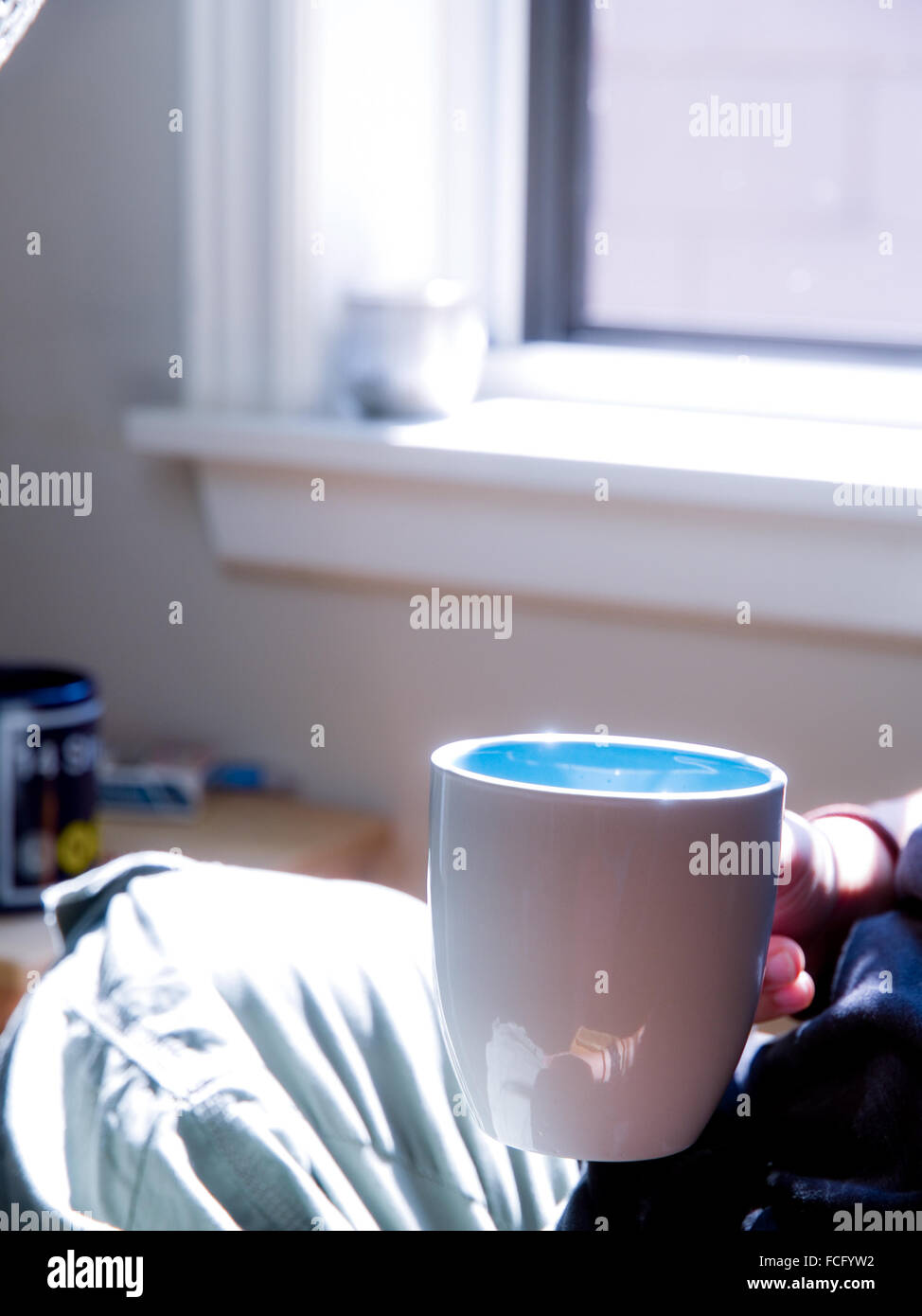 Close-up of blue and white coffee cup being help by a woman sitting ...