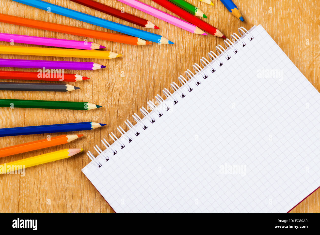 Colored pencils and notepad on wooden table Stock Photo - Alamy