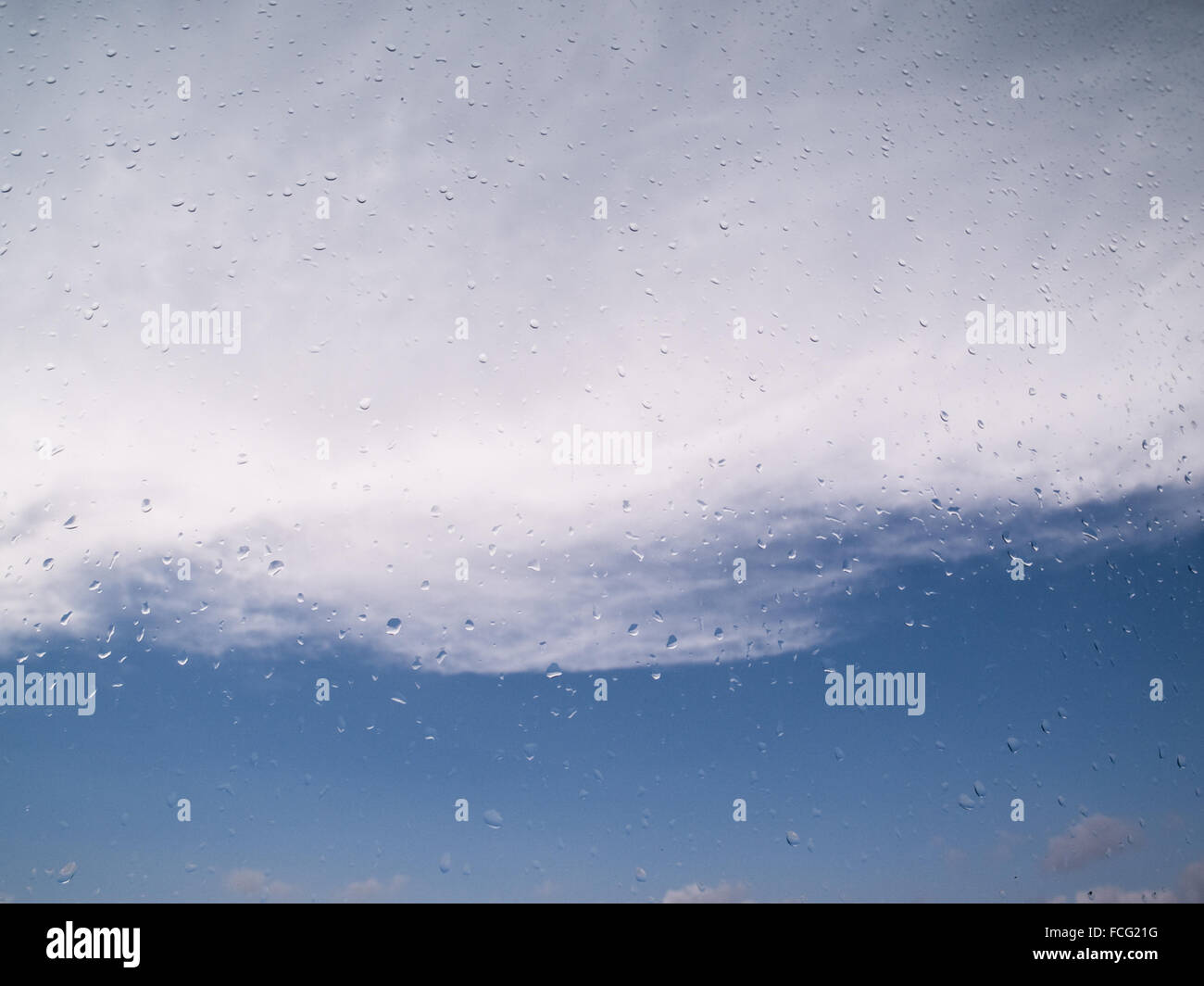 Rain drops on window looking out at blue sky with clouds Stock Photo ...