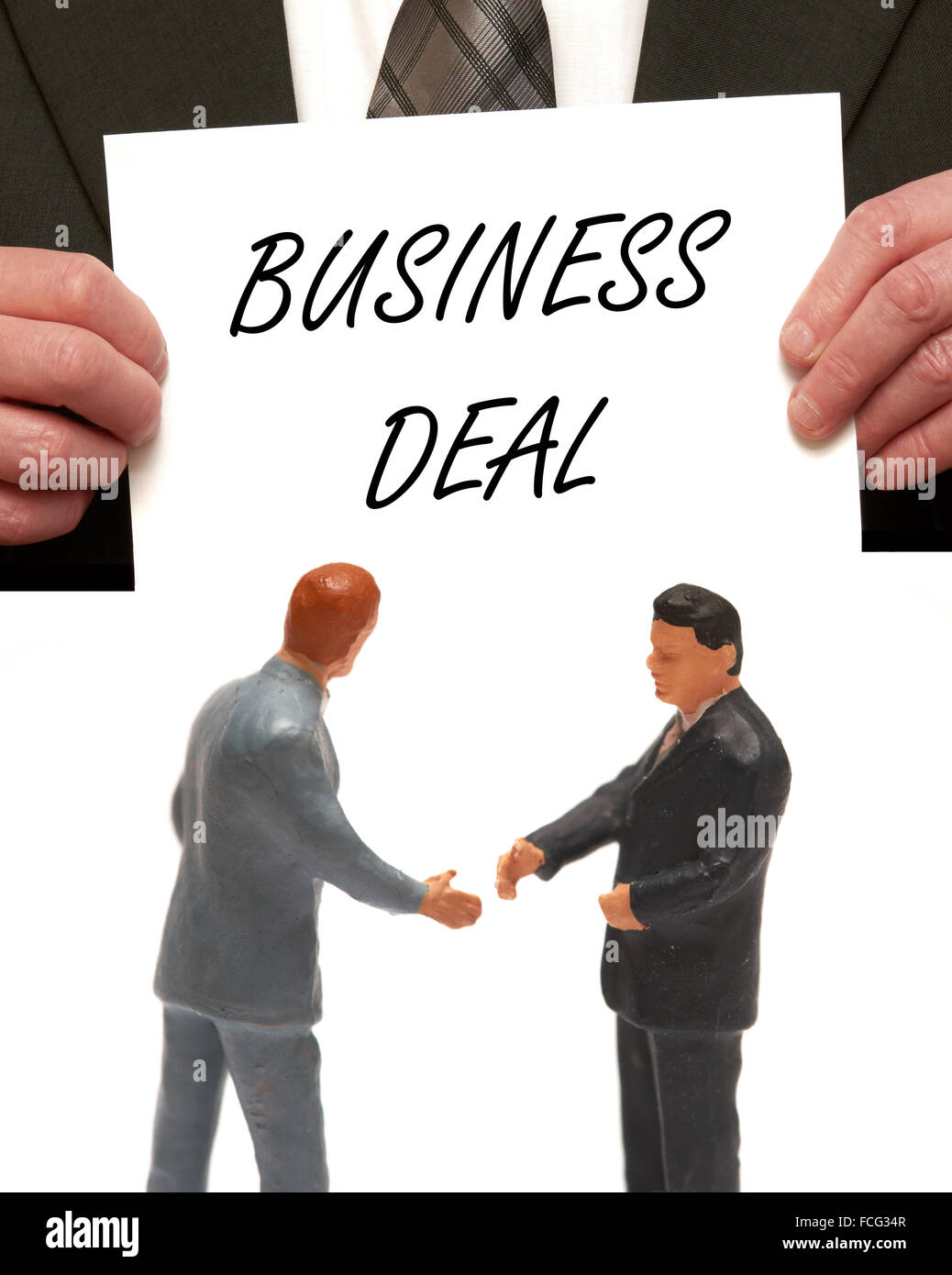 Business deal concept 2 miniature figurines in suits shaking hands ...