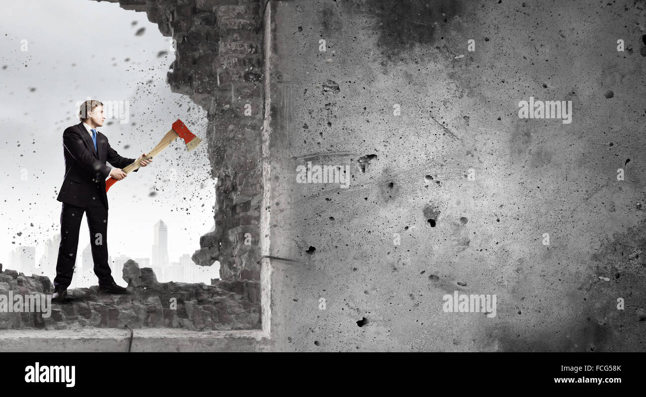 Young businessman breaking cement wall with axe Stock Photo - Alamy