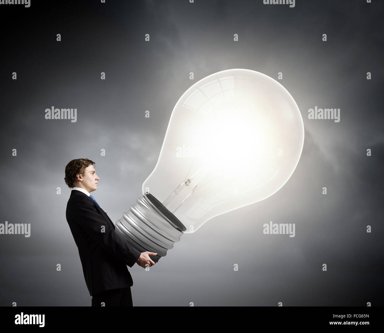 Young businessman carrying big heavy light bulb Stock Photo - Alamy