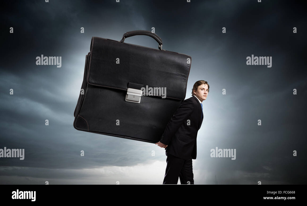 Young determined businessman carrying big heavy suitcase Stock Photo ...