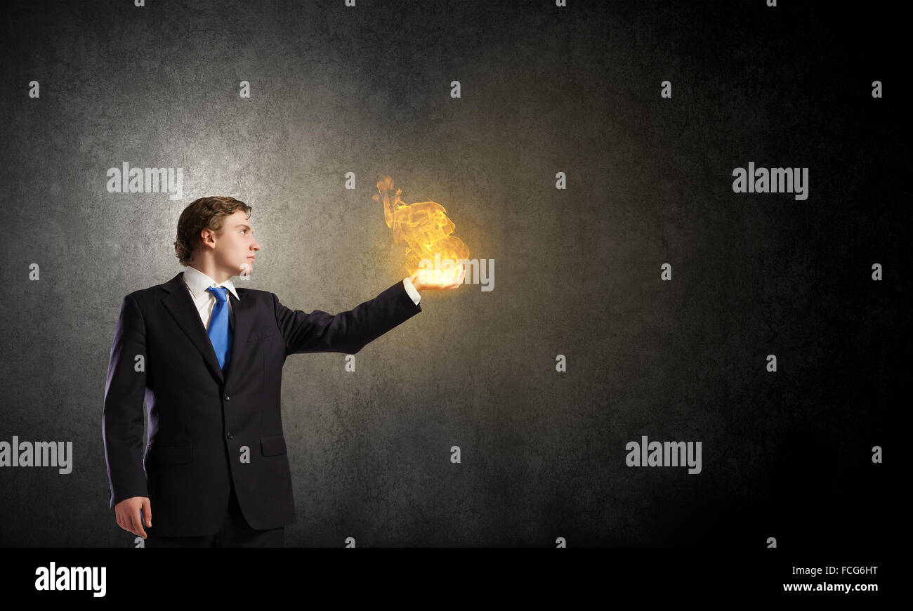 Young businessman holding fire flames in palm Stock Photo - Alamy