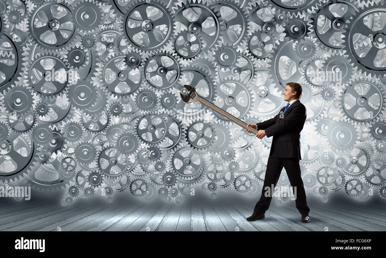Young businessman fixing gears mechanism with wrench Stock Photo - Alamy