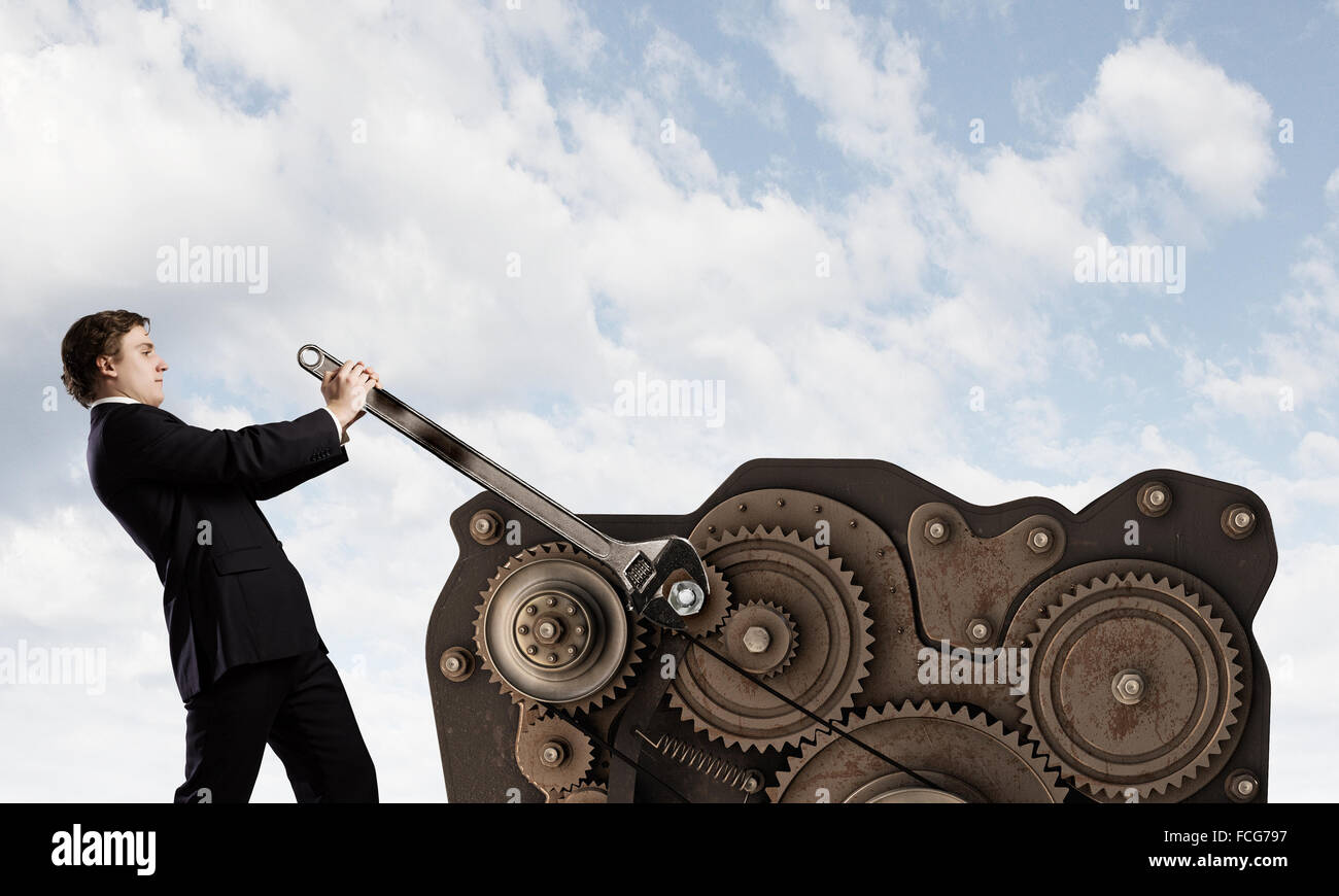 Young businessman fixing gears mechanism with wrench Stock Photo - Alamy