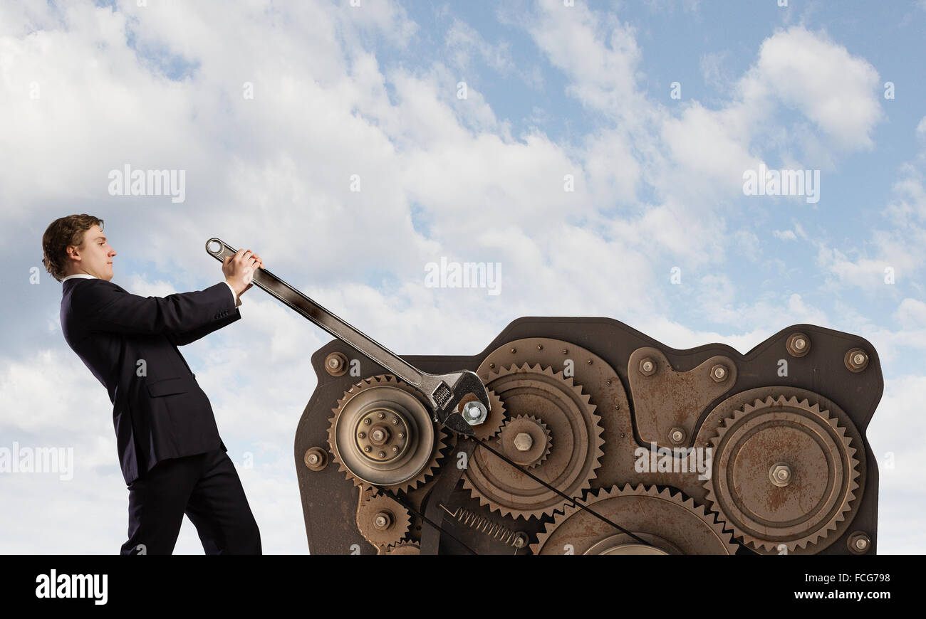 Young businessman fixing gears mechanism with wrench Stock Photo - Alamy