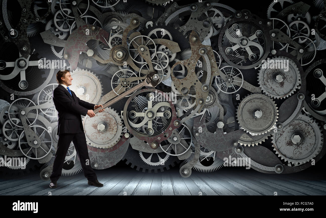 Young businessman fixing gears mechanism with wrench Stock Photo - Alamy