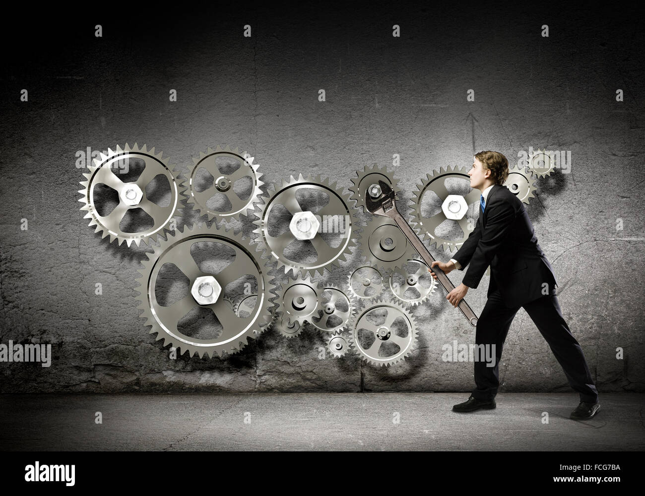 Young businessman fixing gears mechanism with wrench Stock Photo - Alamy