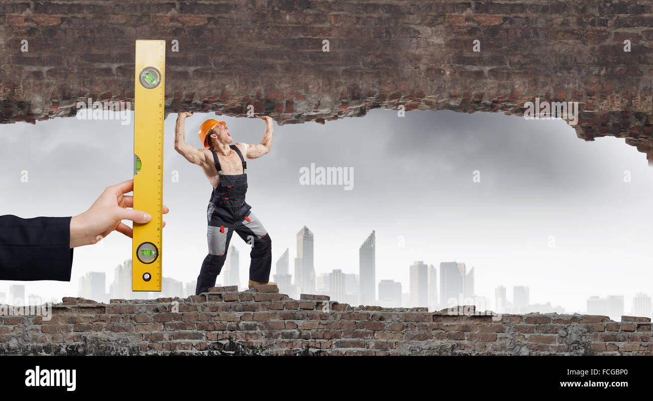 Strong man builder lifting up brick wall Stock Photo - Alamy