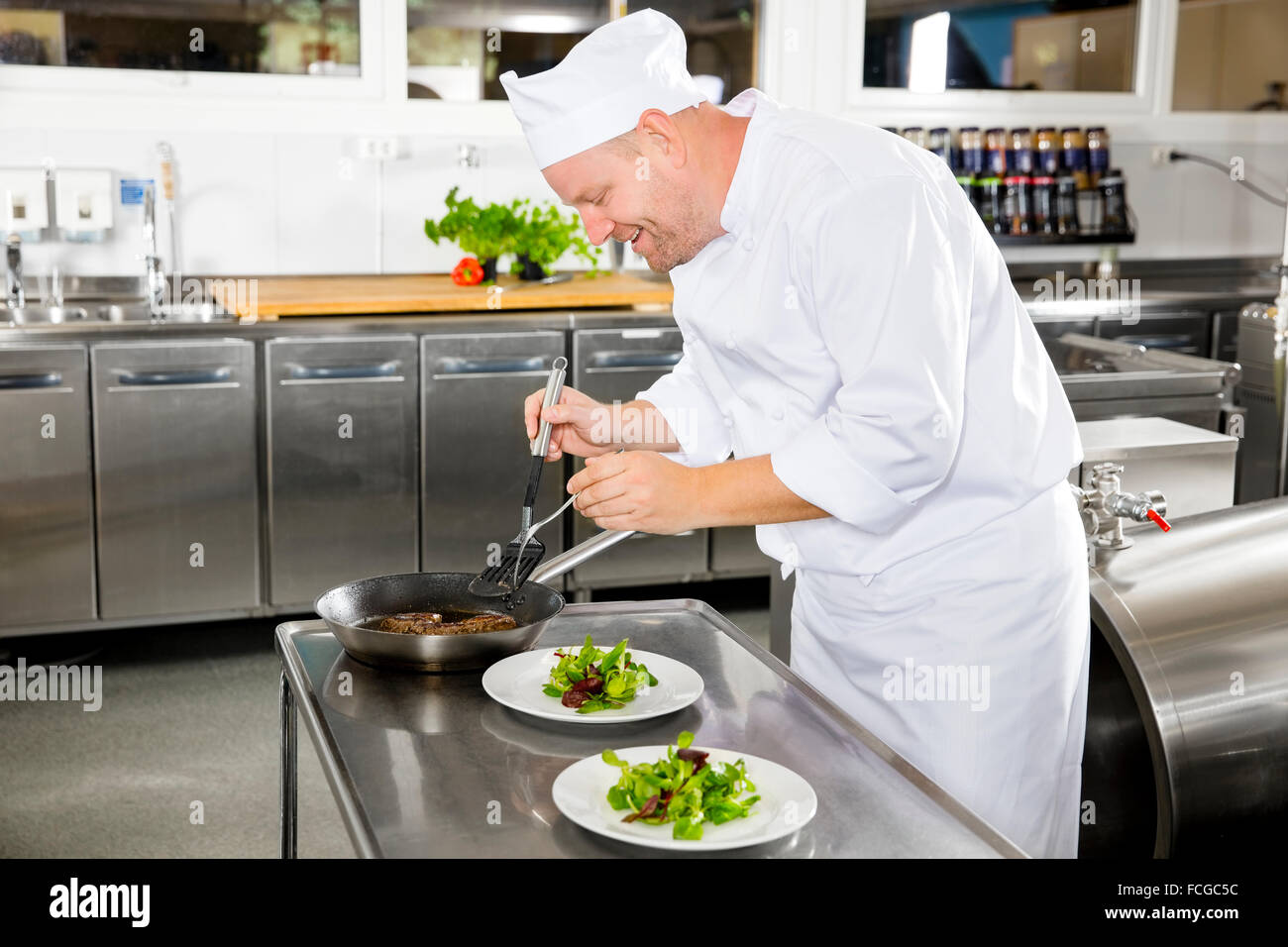 Smiling chef prepares steak dish at restaurant Stock Photo - Alamy