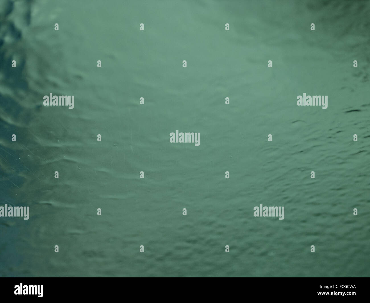 Wet green windshield at the car wash with streaks of water and blurry ...