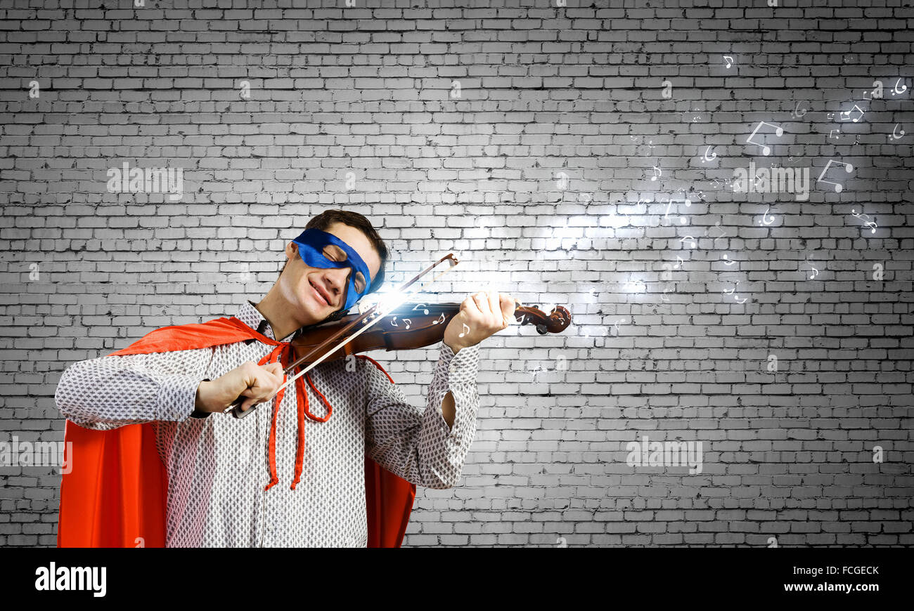 Young man in superhero costume playing violin Stock Photo - Alamy