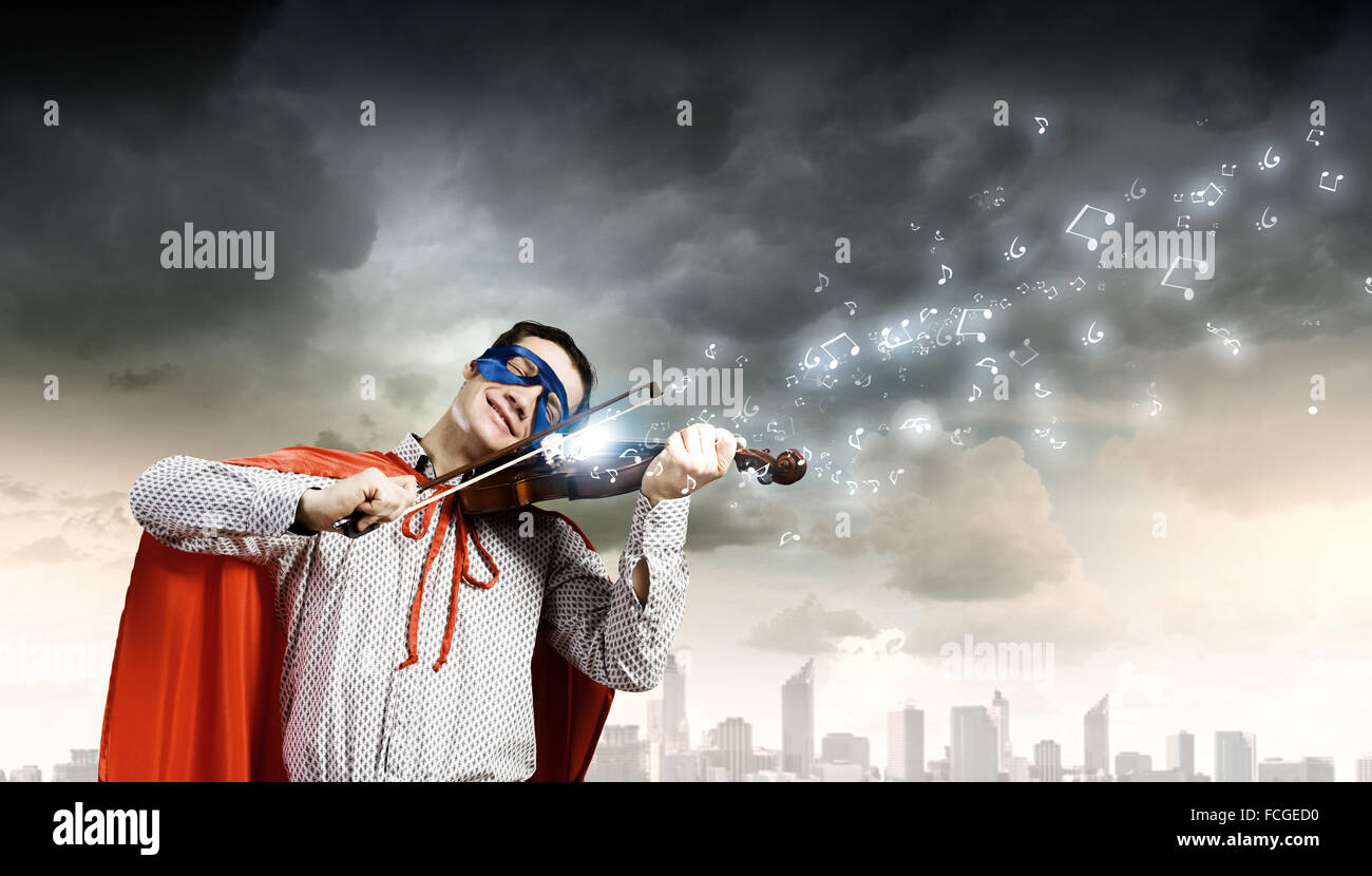 Young man in superhero costume playing violin Stock Photo - Alamy