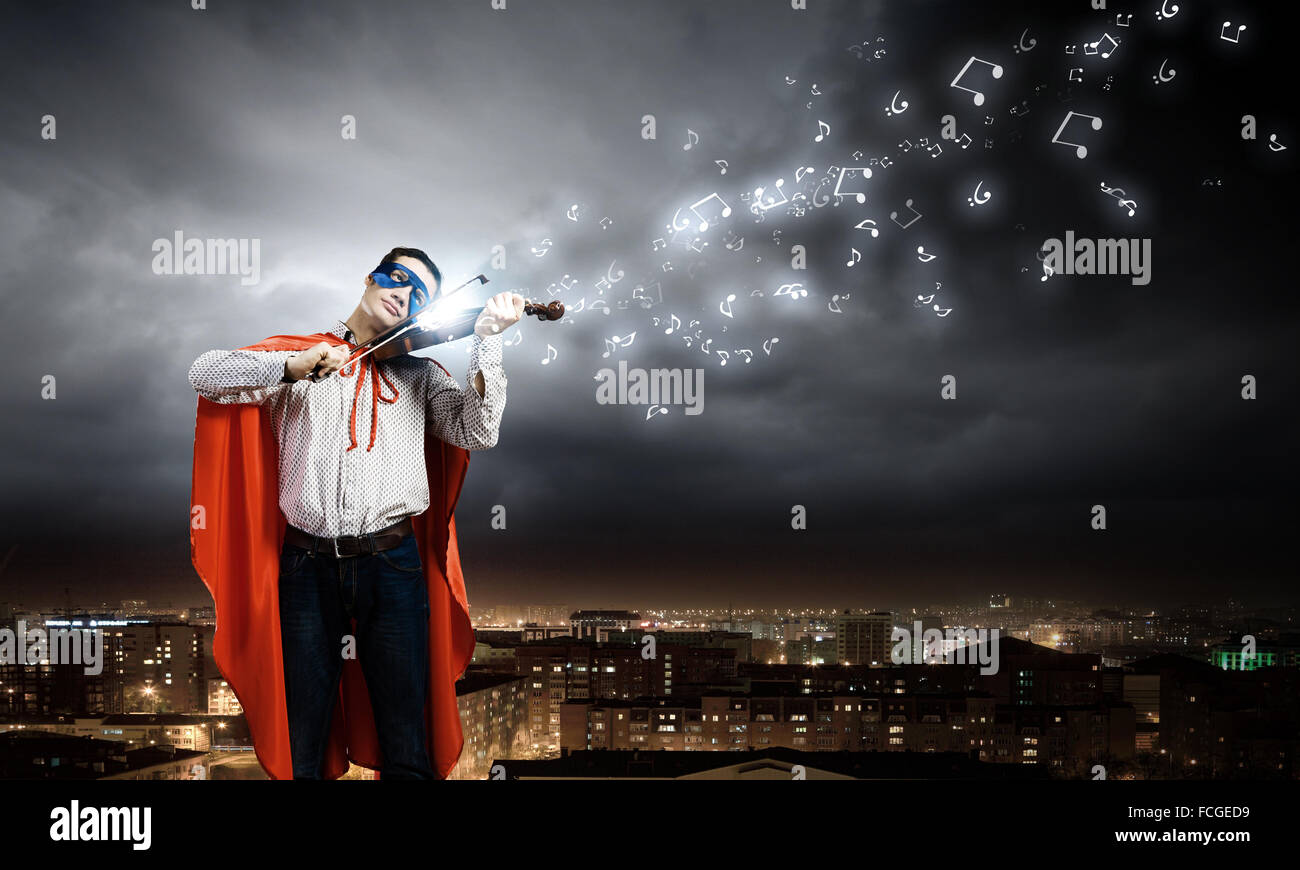 Young man in superhero costume playing violin Stock Photo - Alamy