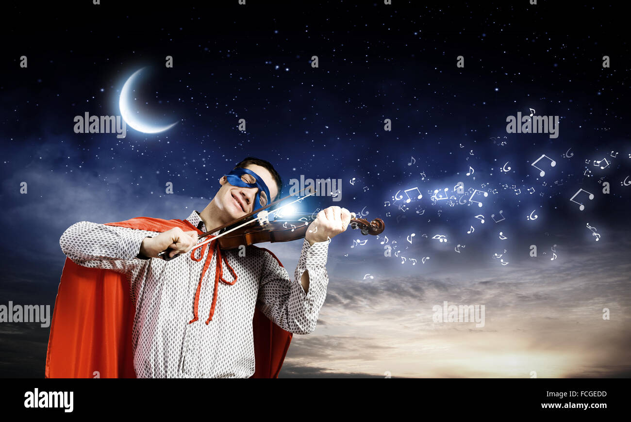 Young man in superhero costume playing violin Stock Photo - Alamy