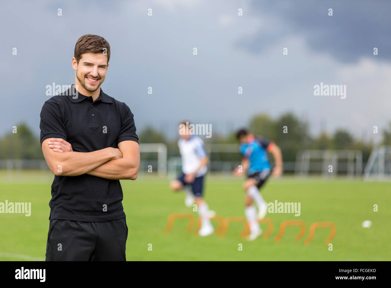 Portrait of smiling coach soccer players in background Stock Photo - Alamy
