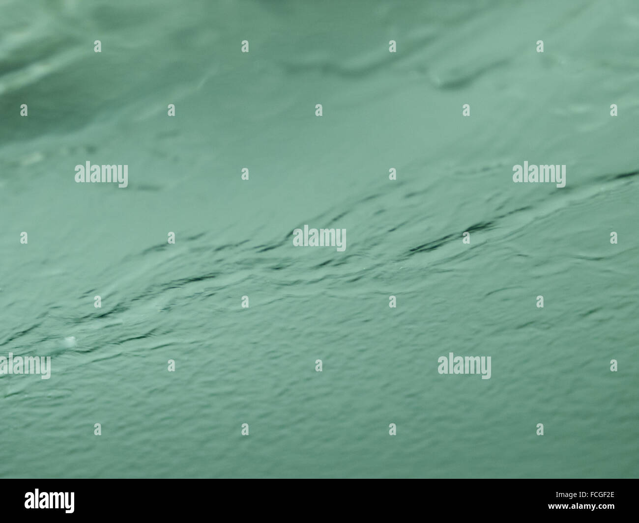 Wet green windshield at the car wash with streaks of water and blurry ...