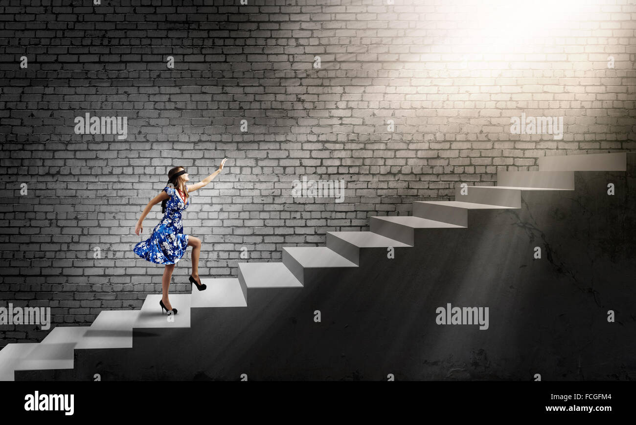 Young woman in blue dress walking on ladder Stock Photo - Alamy