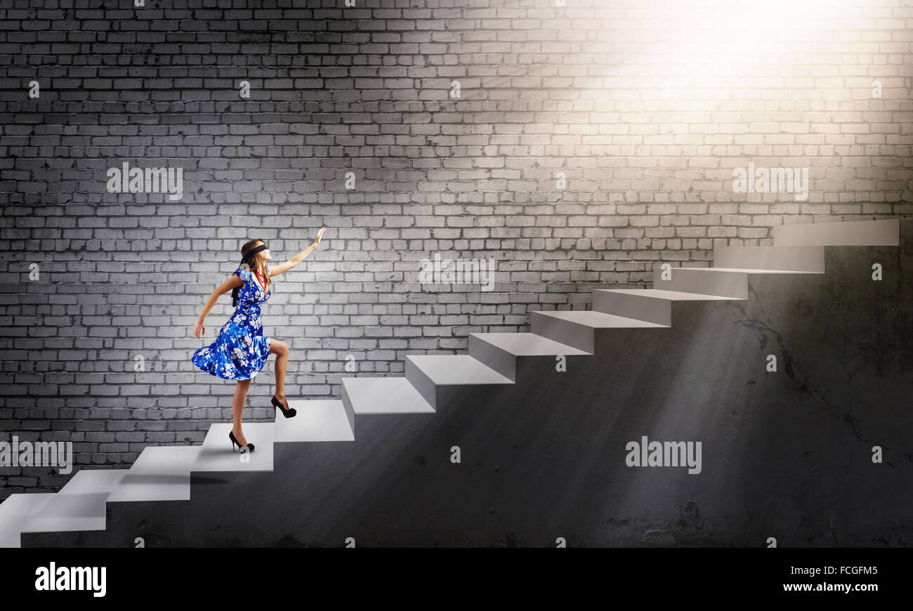 Young woman in blue dress walking on ladder Stock Photo - Alamy