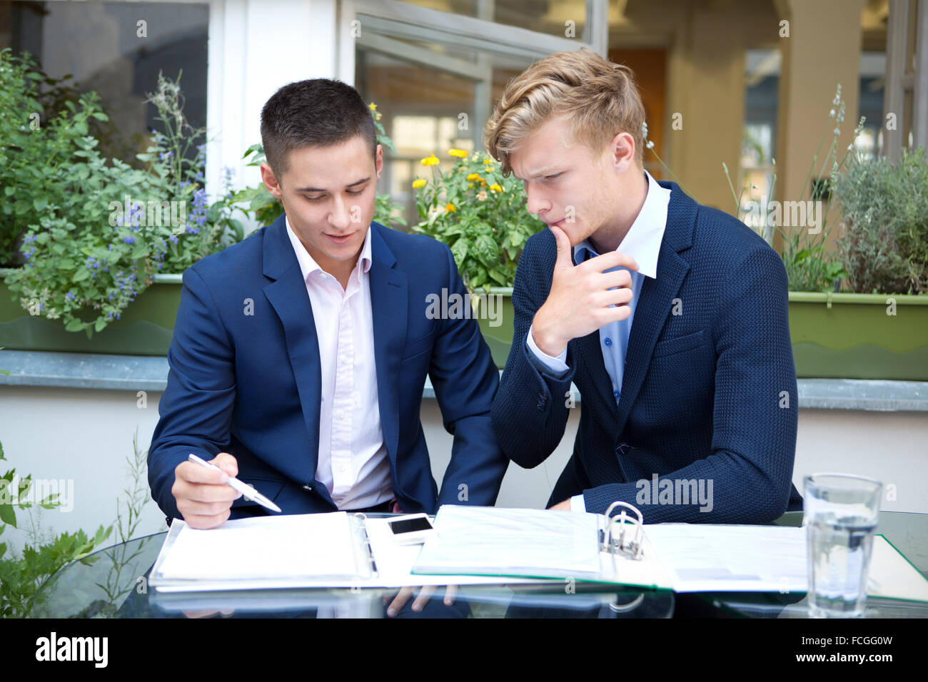 Two businessmen discussing paper Stock Photo - Alamy