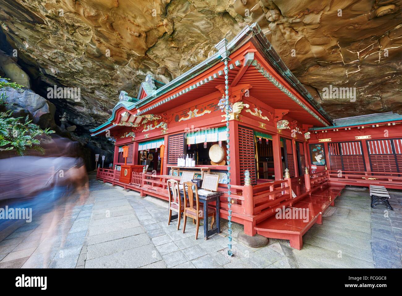 A japanese tourist walking past the main shrine set in the cave of Udo ...