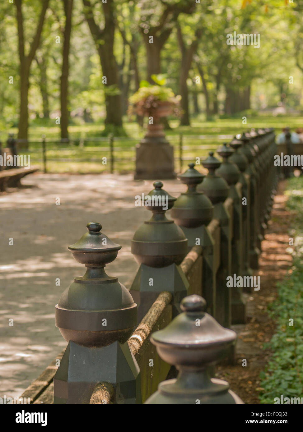 Green metal fence posts and paved pathway at central park in Manhattan ...