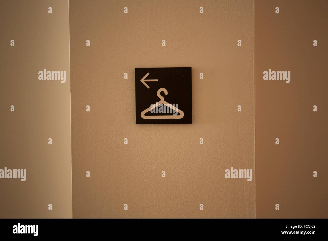 Sign on a wall with a coat hanger icon and an arrow Stock Photo - Alamy