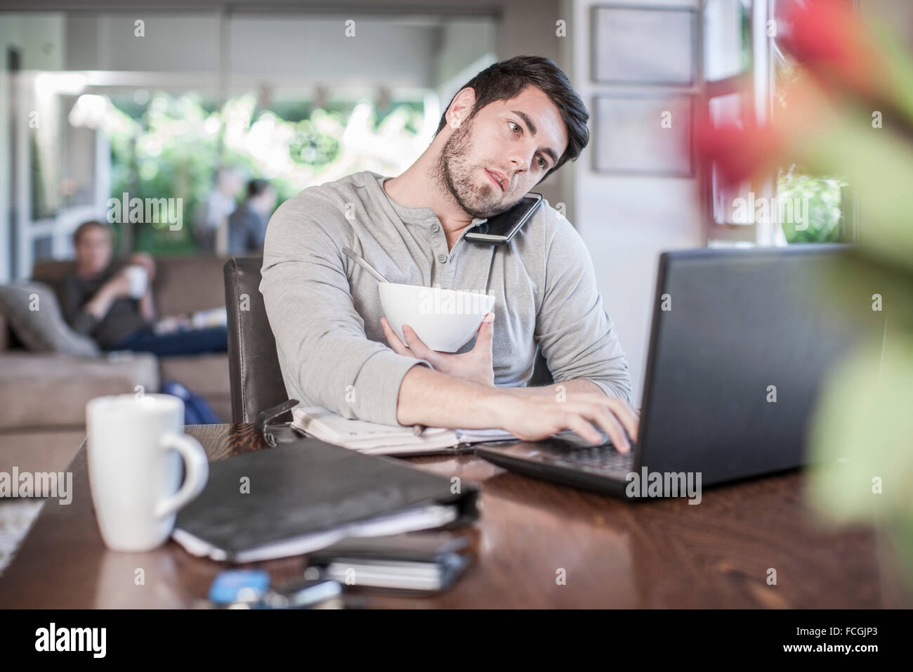 Man sitting at dining room table working at home Stock Photo - Alamy