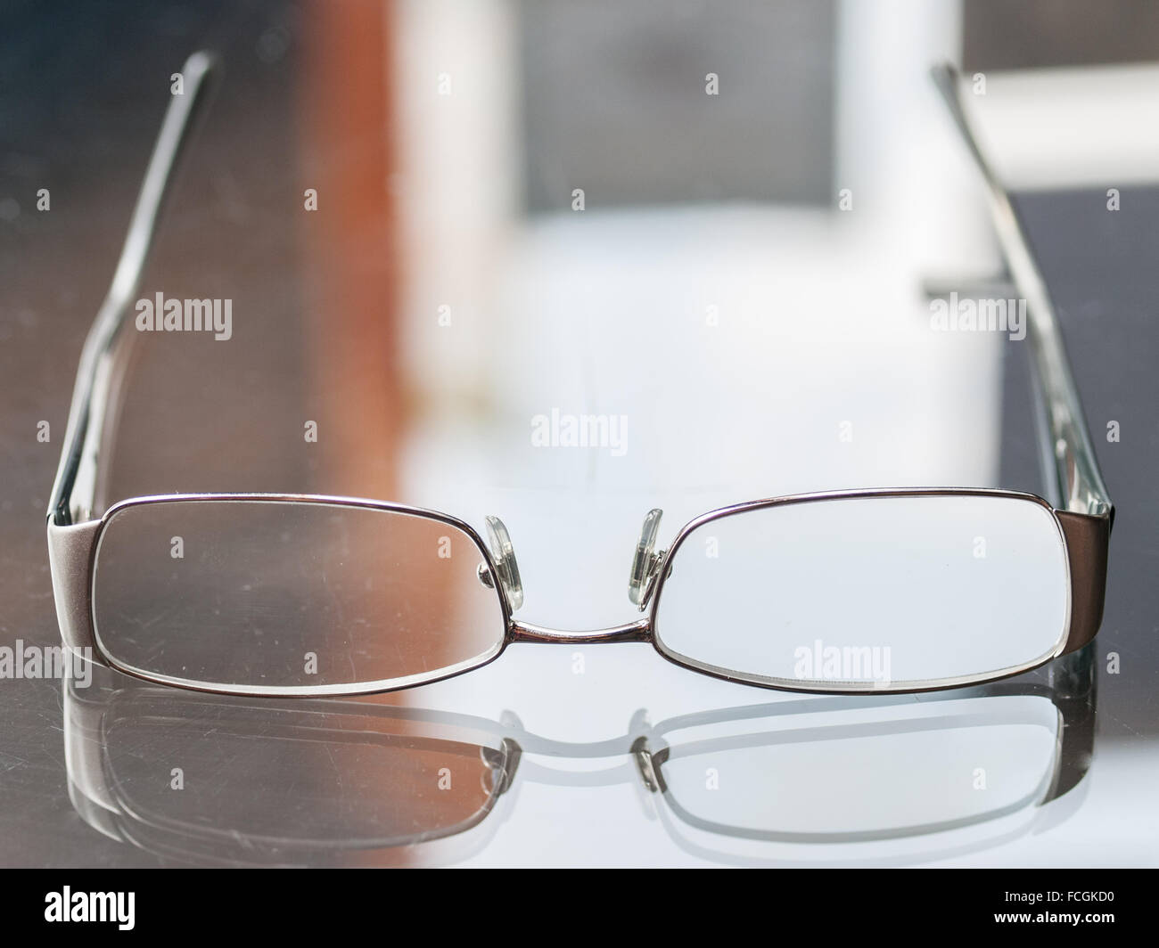 Pair of upside down Versace metal frame glasses on a glass table with ...