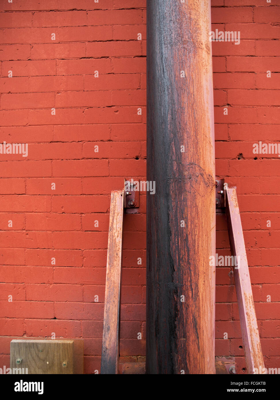Rusted metal post against painted red brick wall in downtown Montreal ...