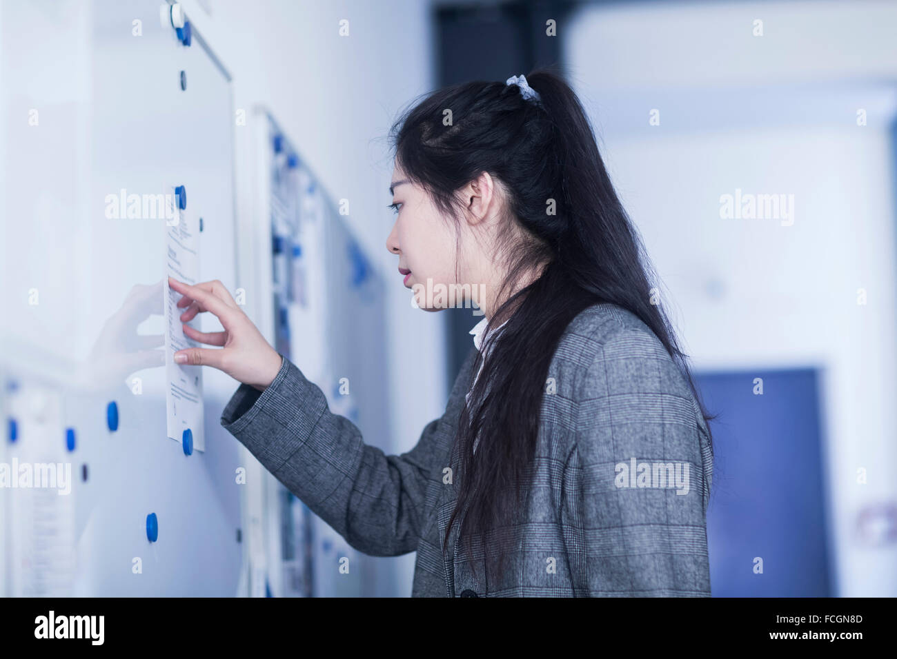 Chinese woman looking at information on pinboard Stock Photo - Alamy