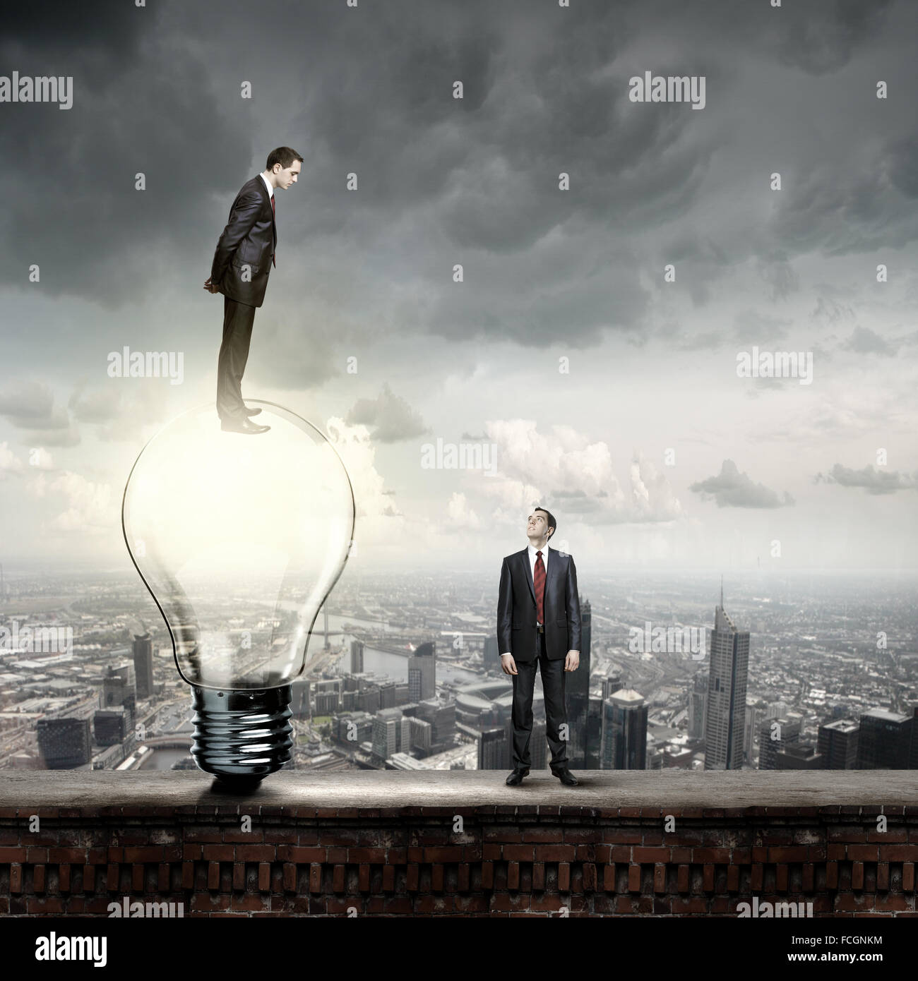 Businessman standing on top of light bulb and looking down Stock Photo ...