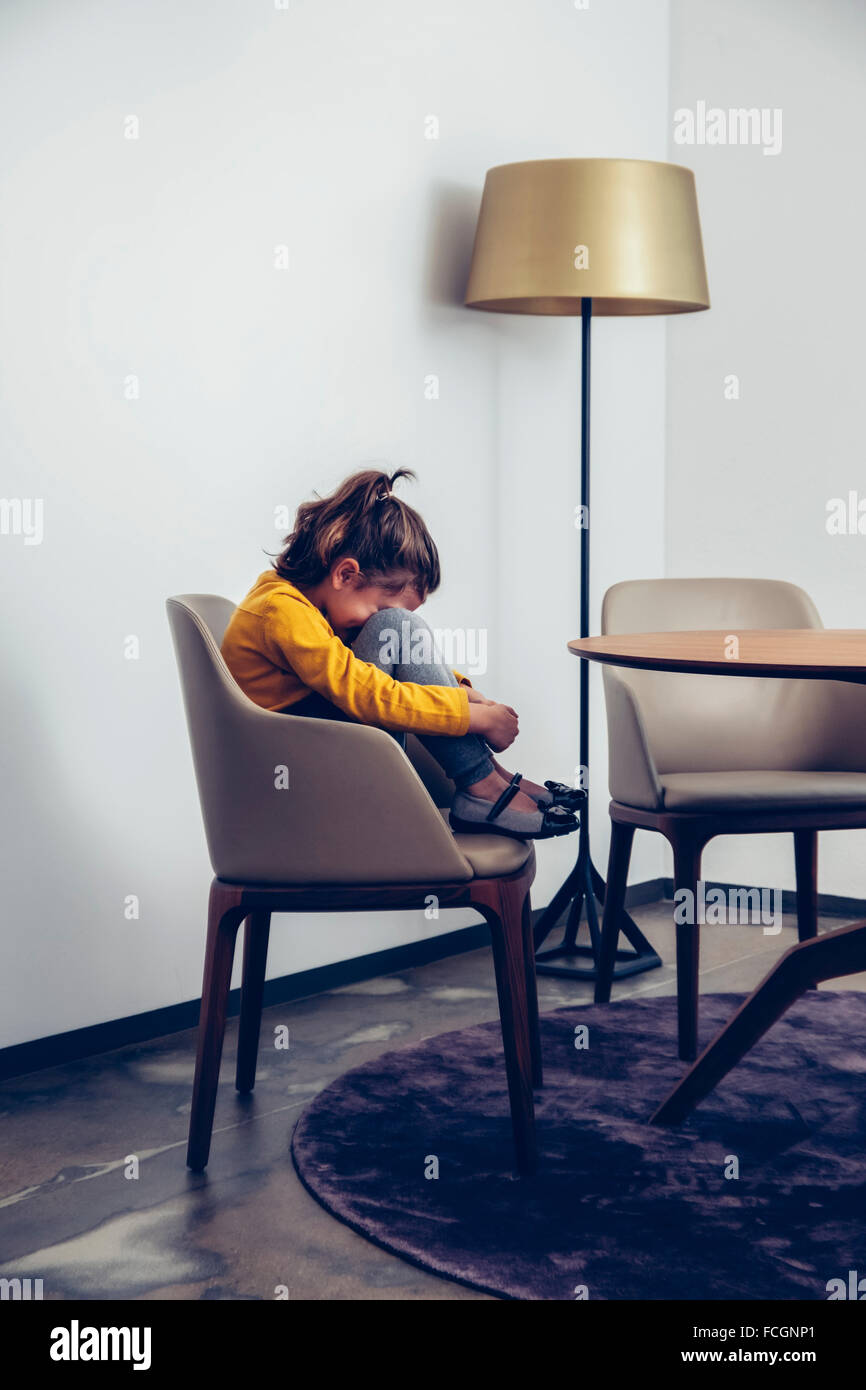 Sad girl sitting on a chair Stock Photo - Alamy