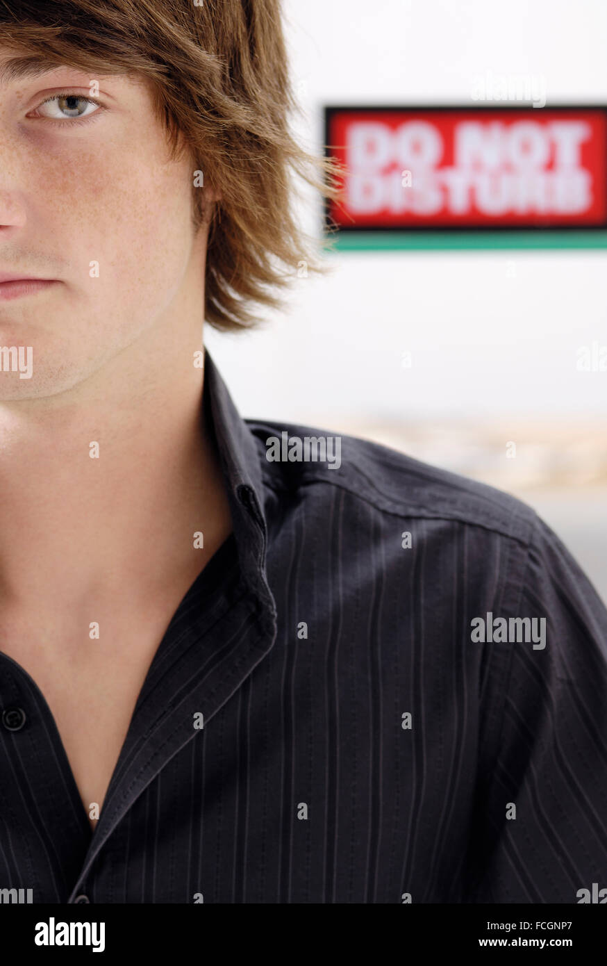 Portrait of teenage boy 'Do not disturb' sign in the background close ...