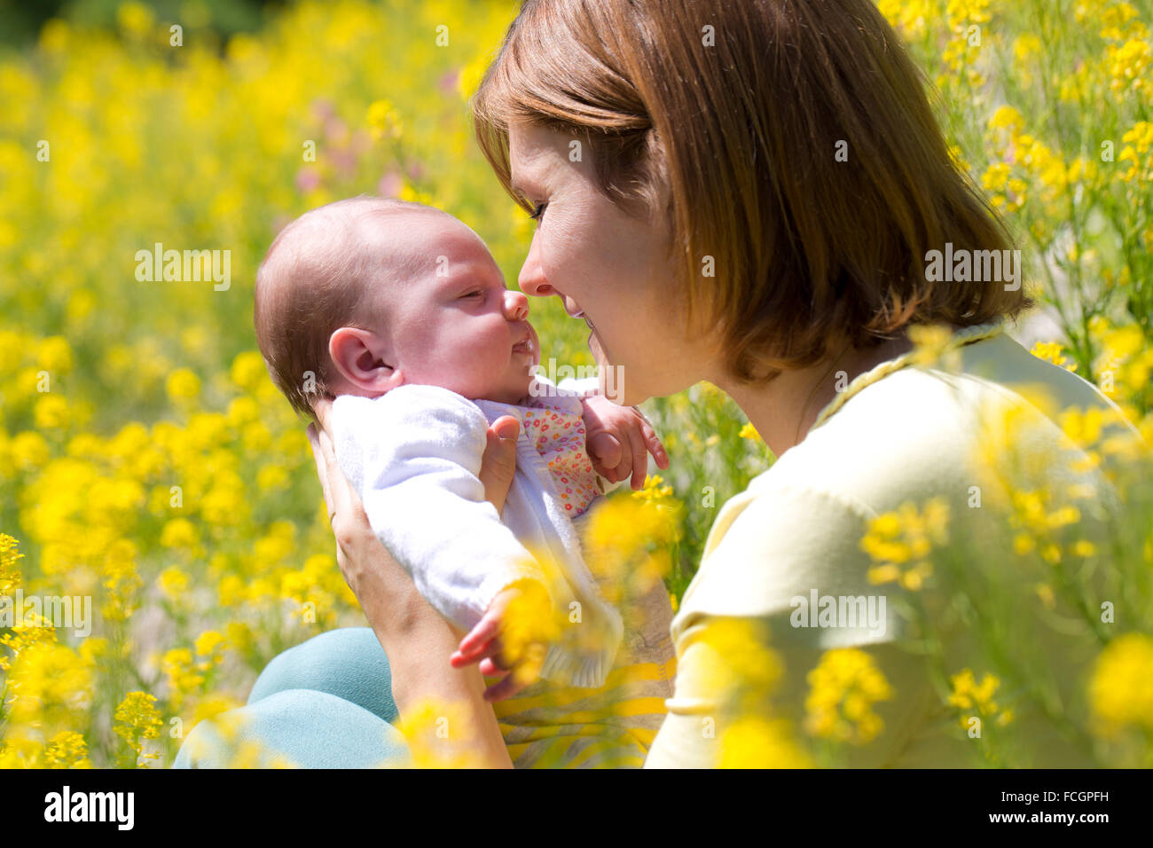 Mother her baby girl on yellow blossoming field of flowers Stock Photo ...
