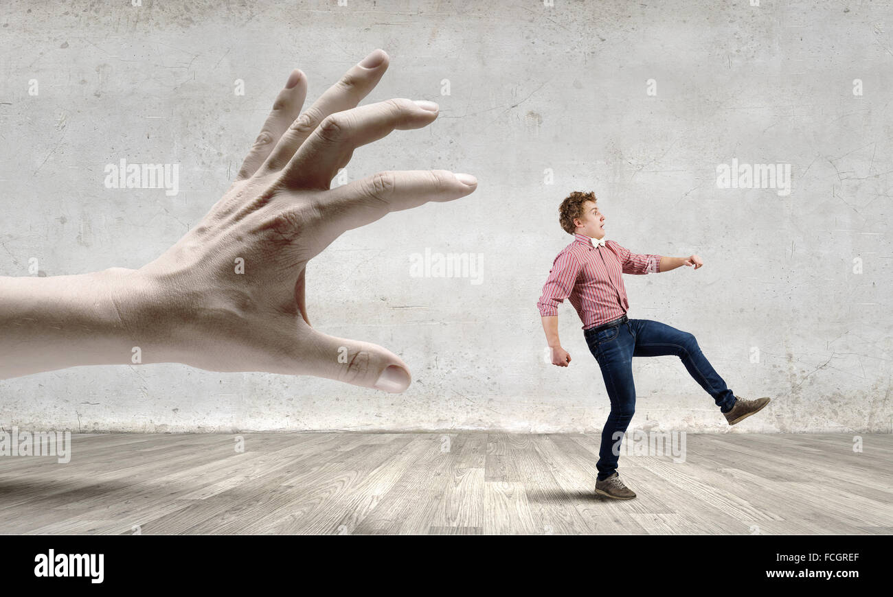 Young man trying to run away from big male hand Stock Photo - Alamy