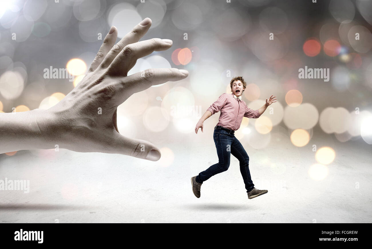 Young man trying to run away from big male hand Stock Photo - Alamy