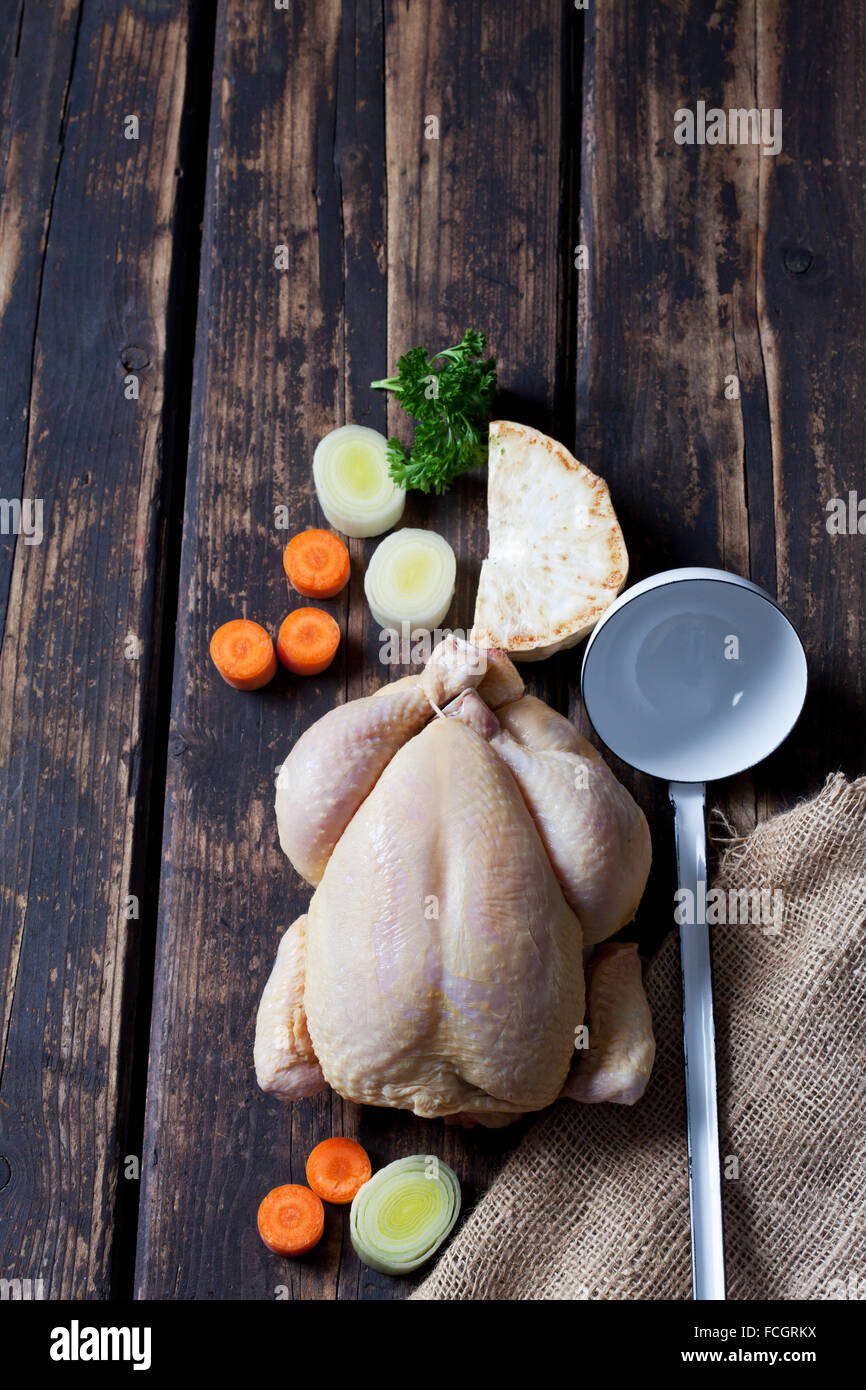 Raw corn-fed chicken greens and soupl laddle on dark wood Stock Photo ...