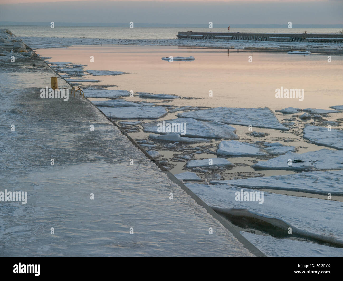 Ice covered pier and Lake Ontario at sunset in winter in Oakville ...