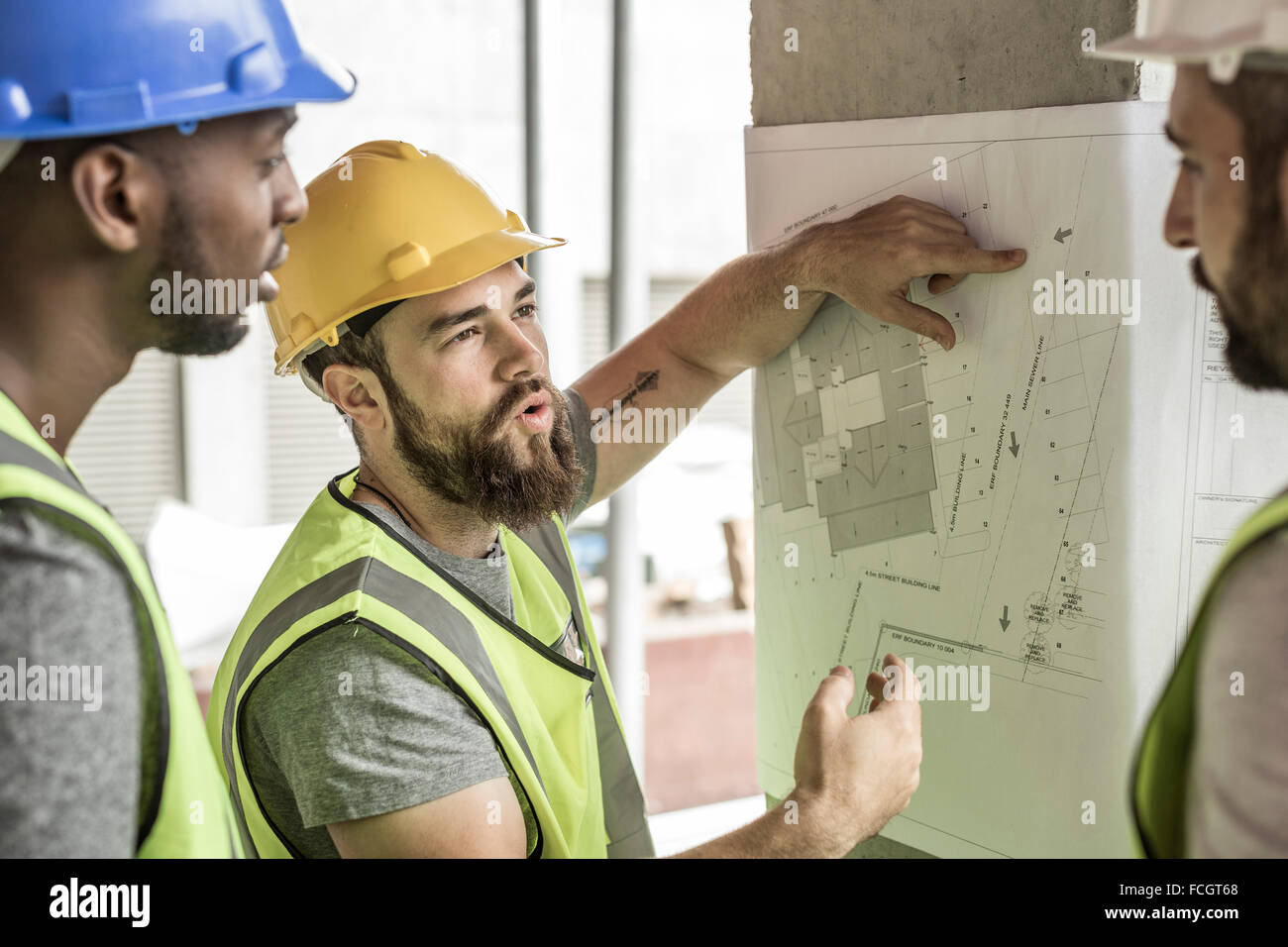 Construction workers discussing building plan in construction site ...