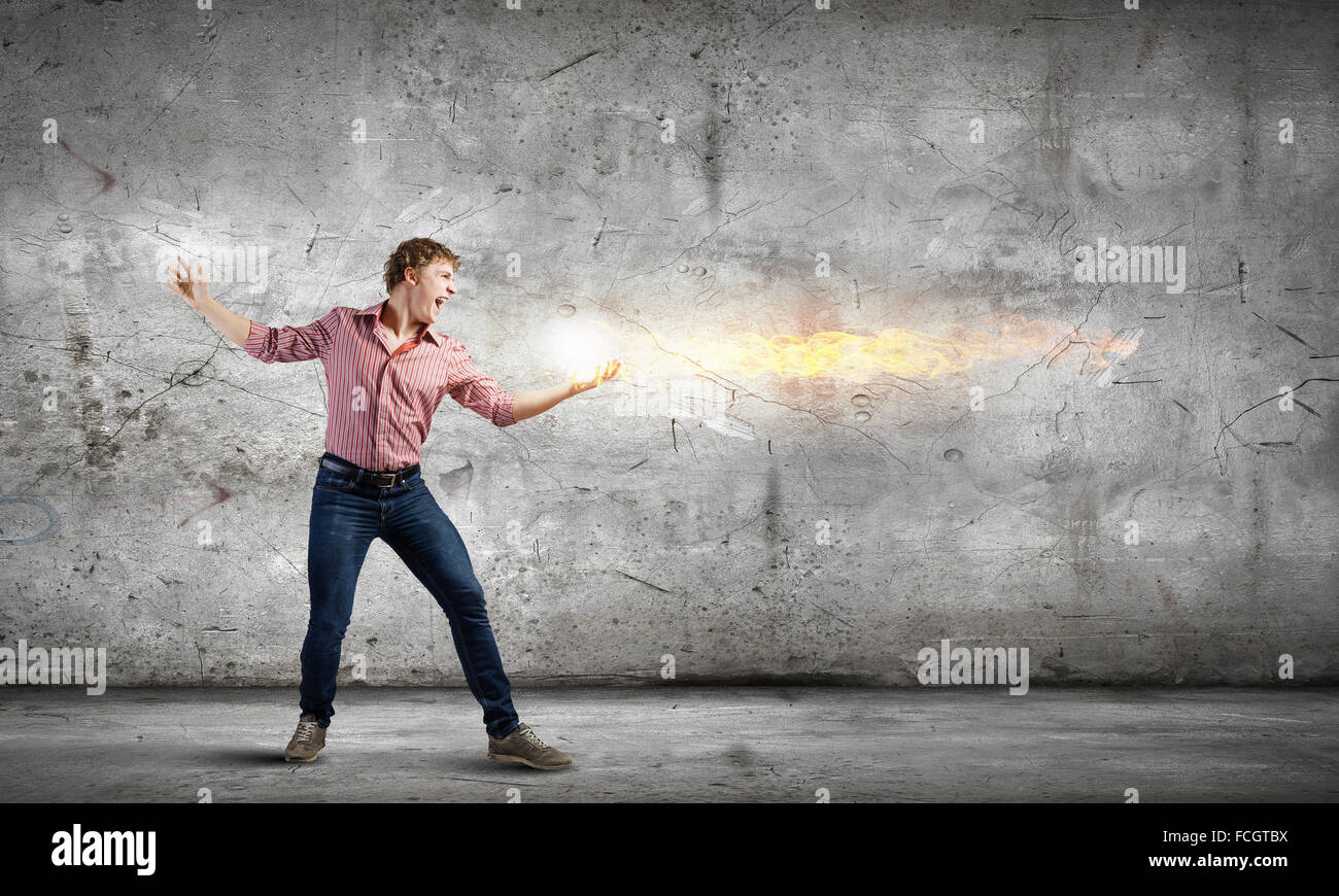 Young man in casual throwing fire ball Stock Photo - Alamy