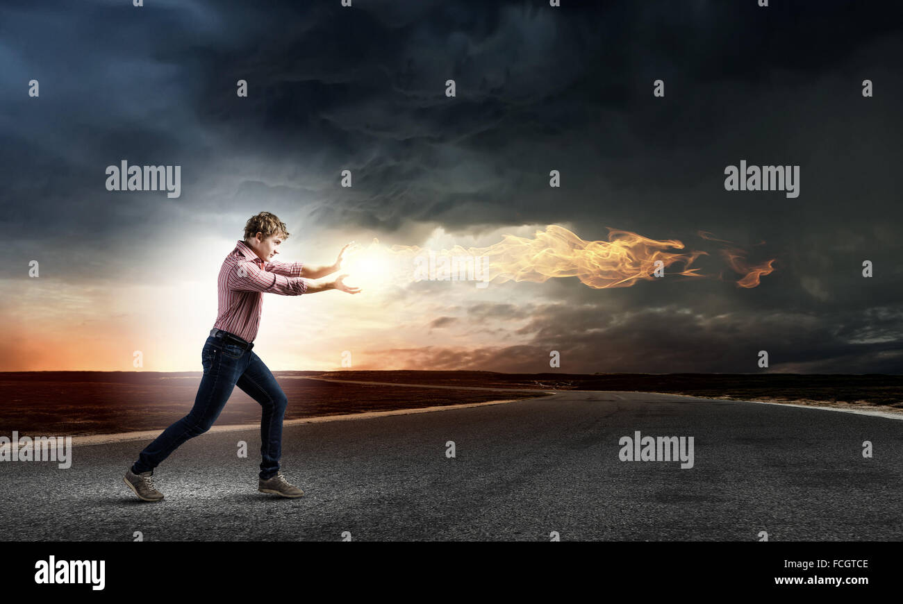 Young man in casual throwing fire ball Stock Photo - Alamy