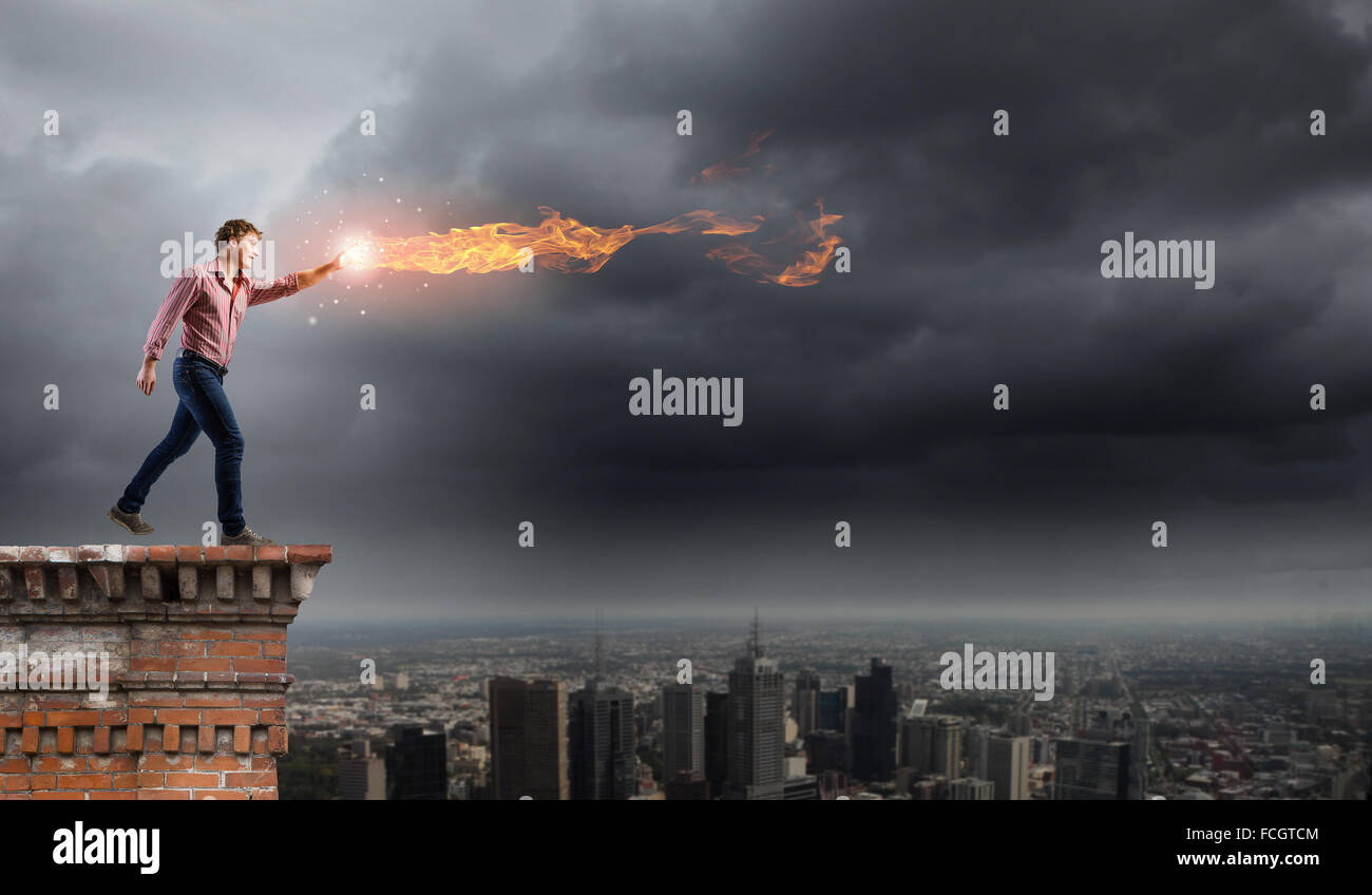 Young man in casual throwing fire ball Stock Photo - Alamy