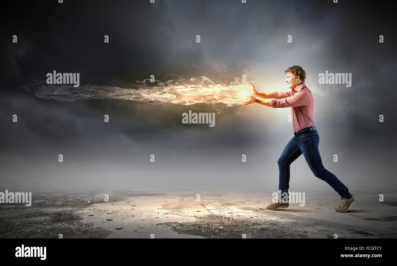 Young man in casual throwing fire ball Stock Photo - Alamy