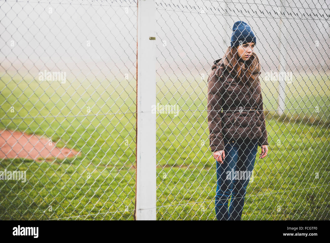 Young woman standing behind mesh wire fence Stock Photo - Alamy