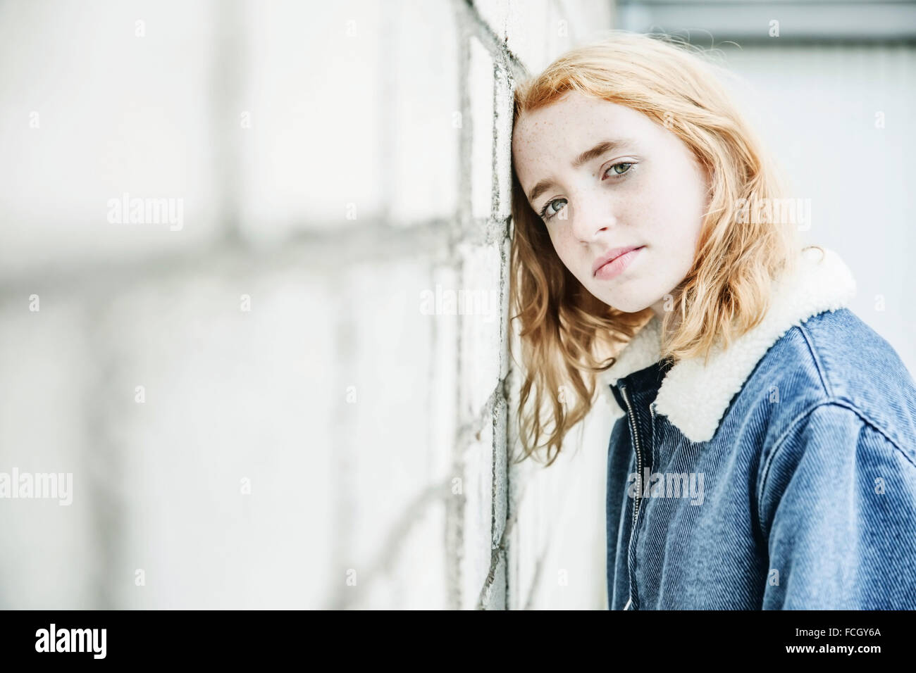 Portrait of girl leaning her head against a wall Stock Photo - Alamy